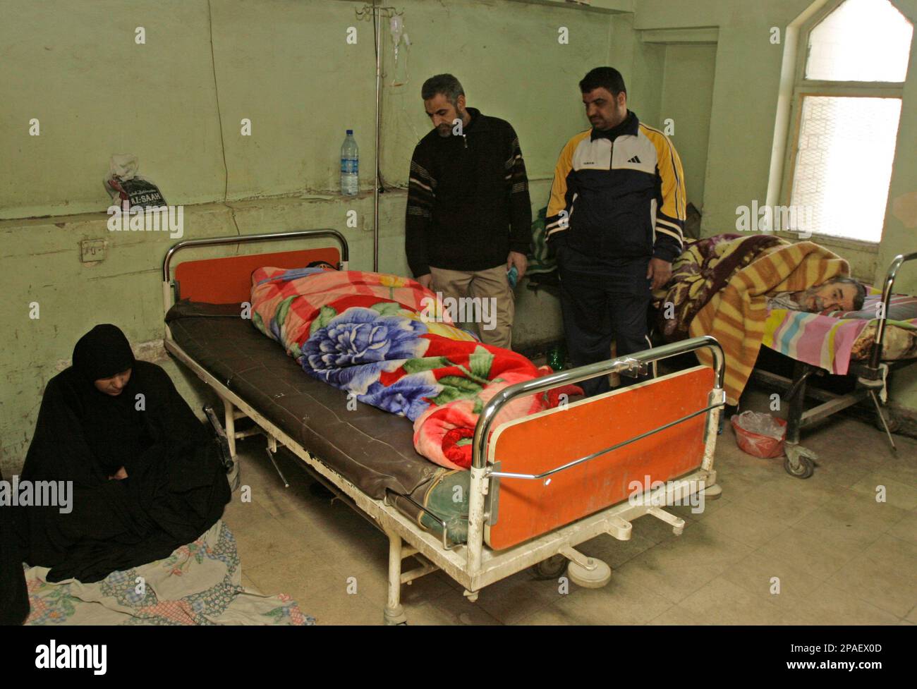 A woman sits by her relative's bed in a hospital in Sadr City, in ...