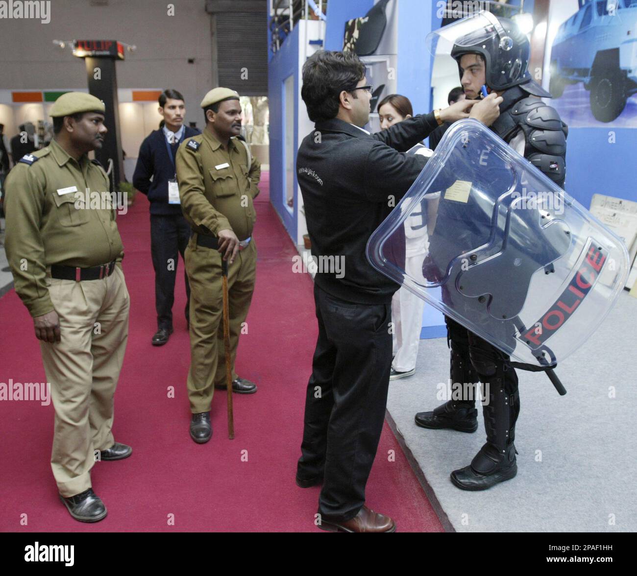 Indian Police officers, left, look on, at a model wearing police riot ...