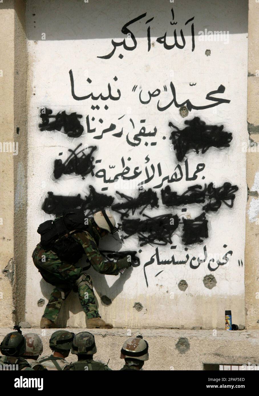 Iraqi soldier paints over a pro-Saddam graffiti in predominantly Sunni ...