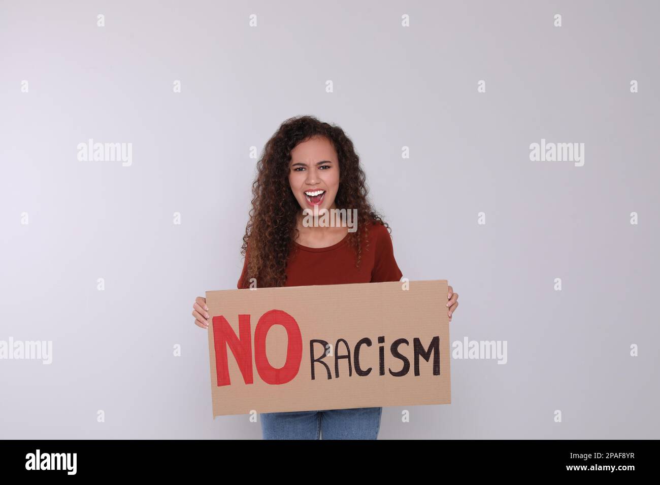Emotional African American woman holding sign with phrase No Racism on ...