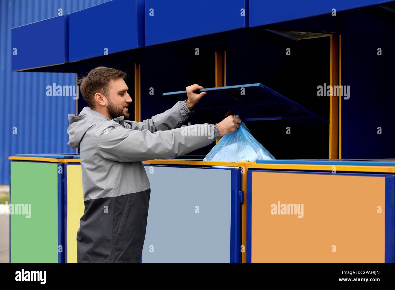 Man throwing garbage into bin at recycling point outdoors Stock Photo ...