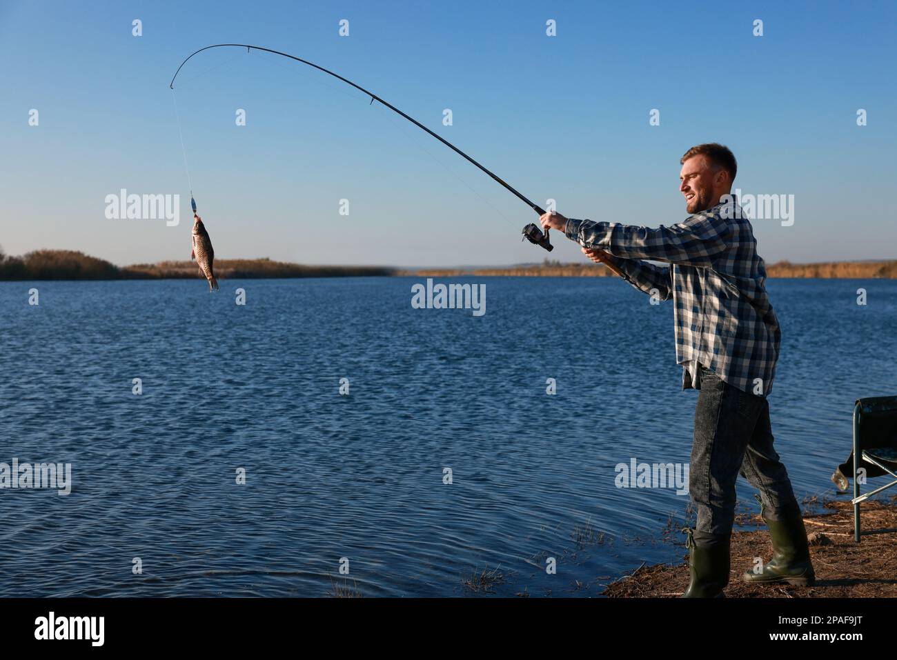 Fisherman catching fish with rod at riverside Stock Photo - Alamy