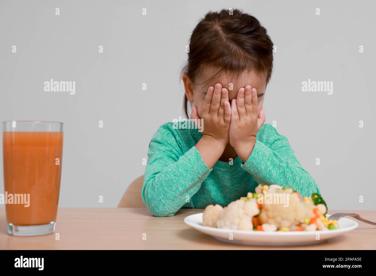 Cute little girl crying and refusing to eat vegetable salad at table on ...