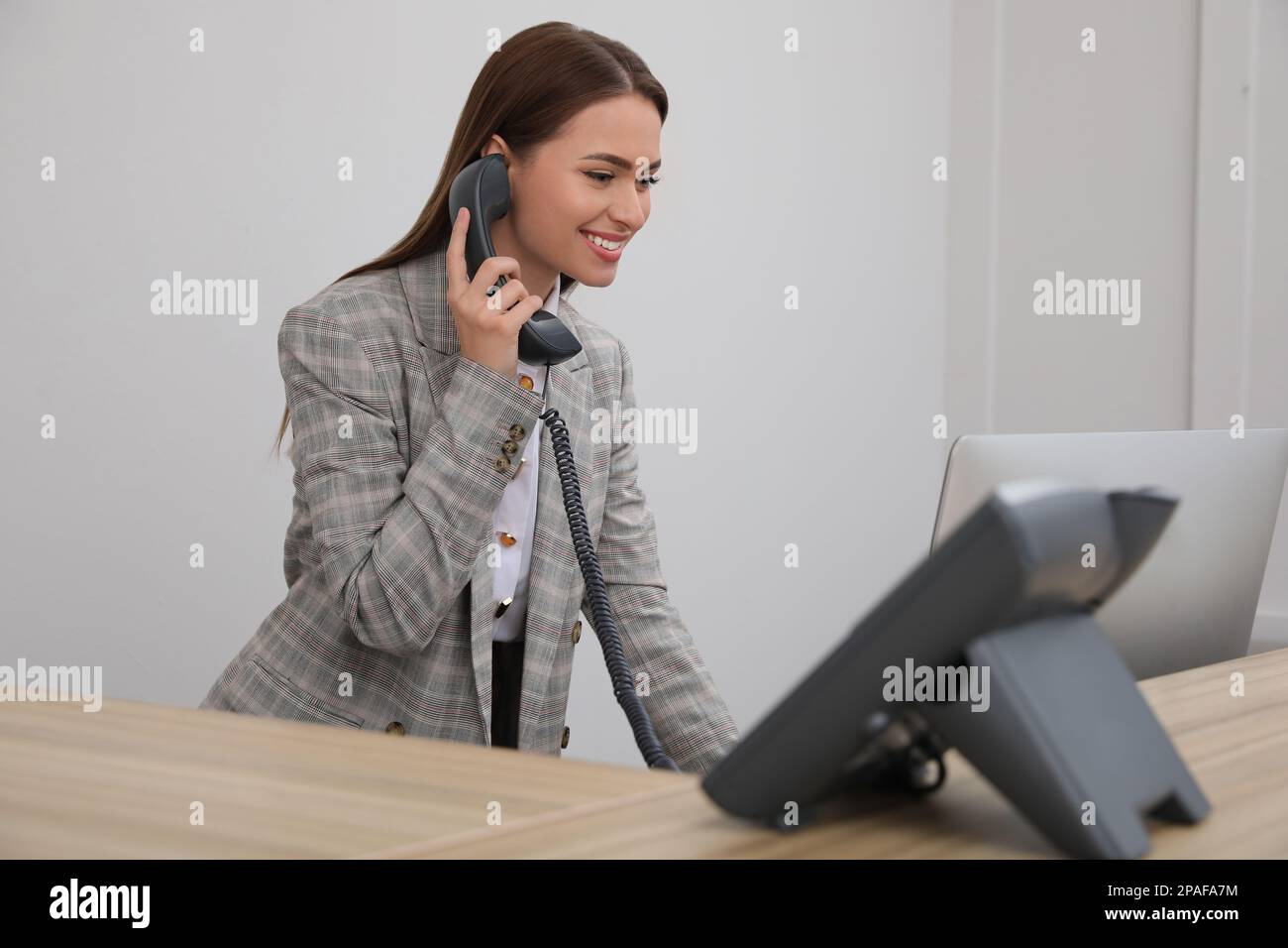 Female receptionist talking on phone at workplace Stock Photo - Alamy