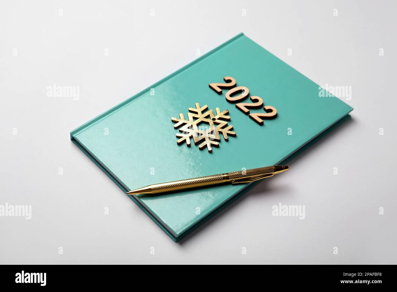 Turquoise planner, pen, wooden numbers and snowflake on white ...
