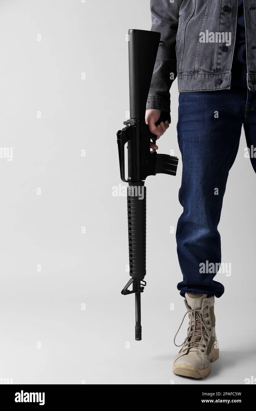 Assault gun. Man holding rifle on light background, closeup Stock Photo ...