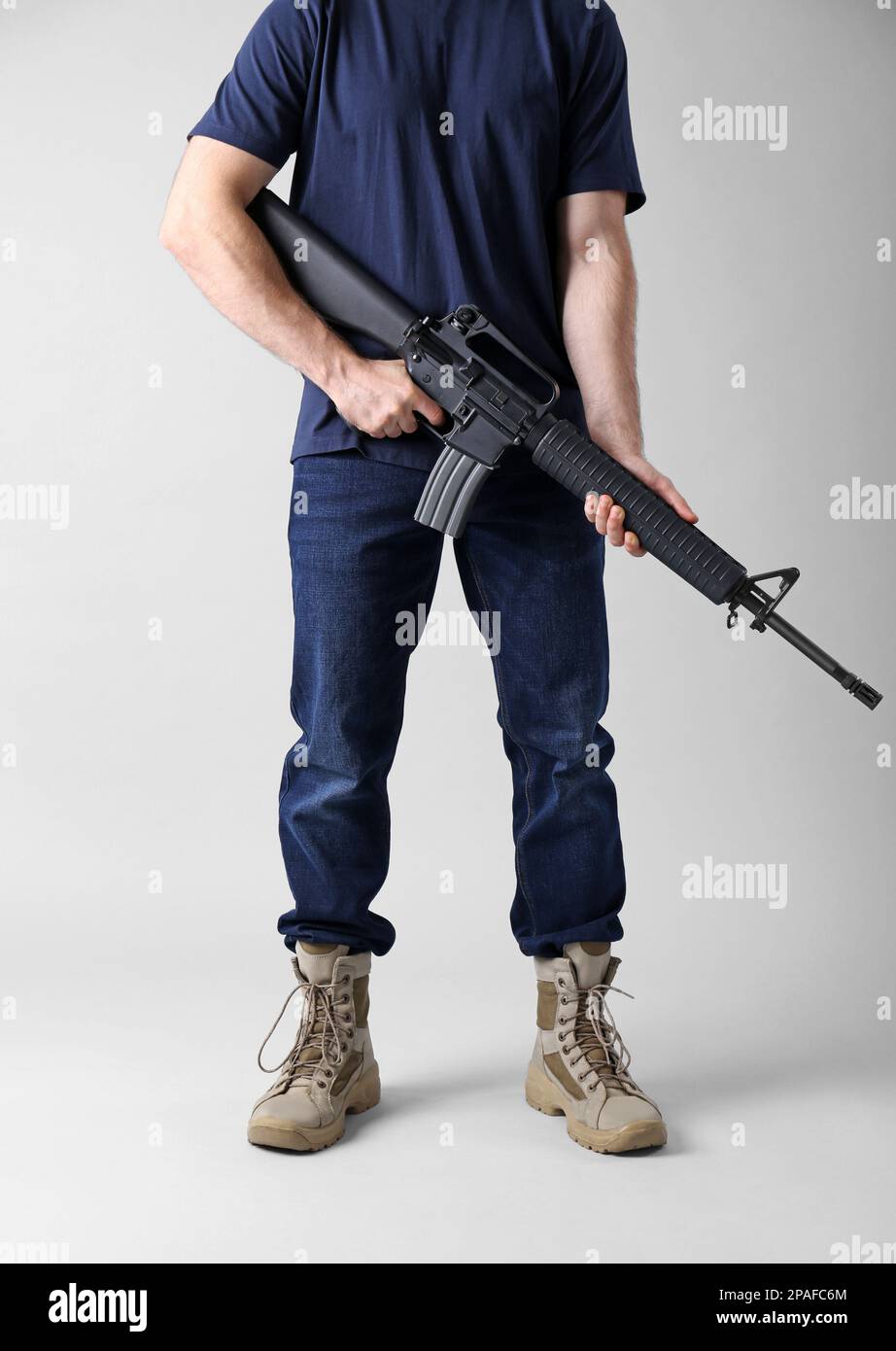 Assault gun. Man holding rifle on light background, closeup Stock Photo ... Assault gun. Man holding rifle on light background, closeup Stock Photo ...