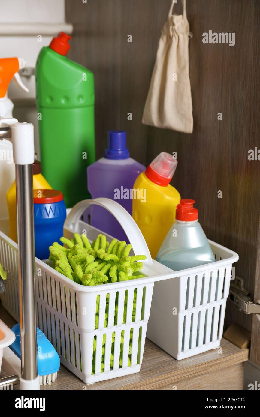 Open under sink cabinet with different cleaning supplies in kitchen ...
