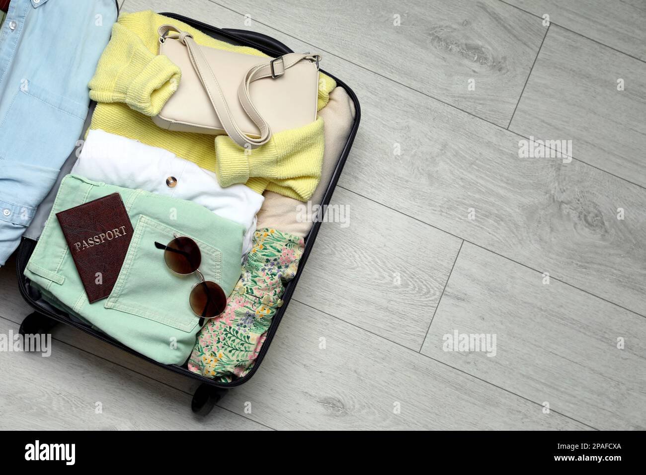 Open suitcase with clothes and accessories on floor, top view. Space ...