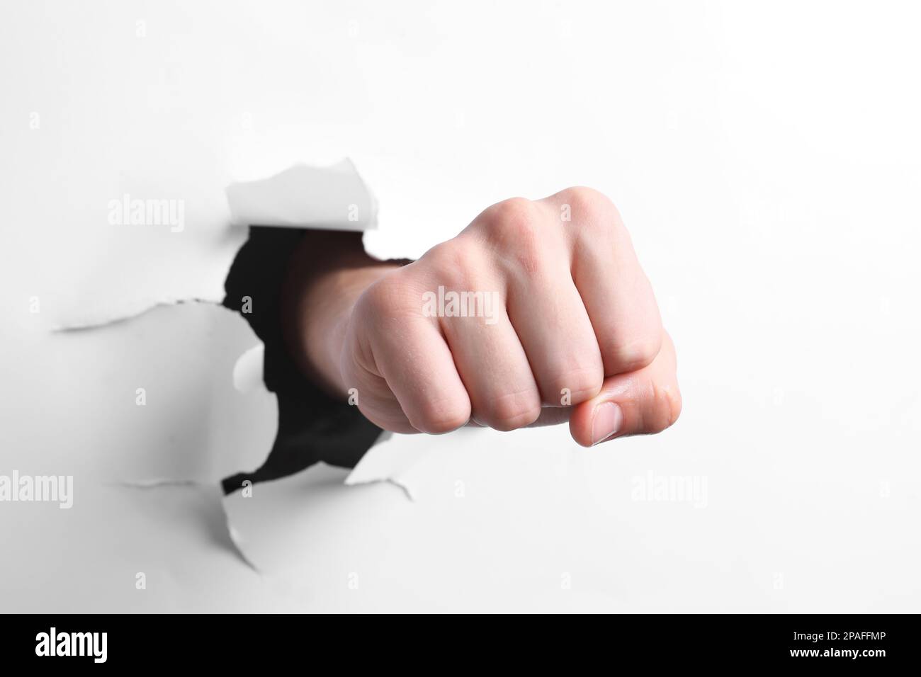 Man breaking through white paper with fist, closeup Stock Photo - Alamy