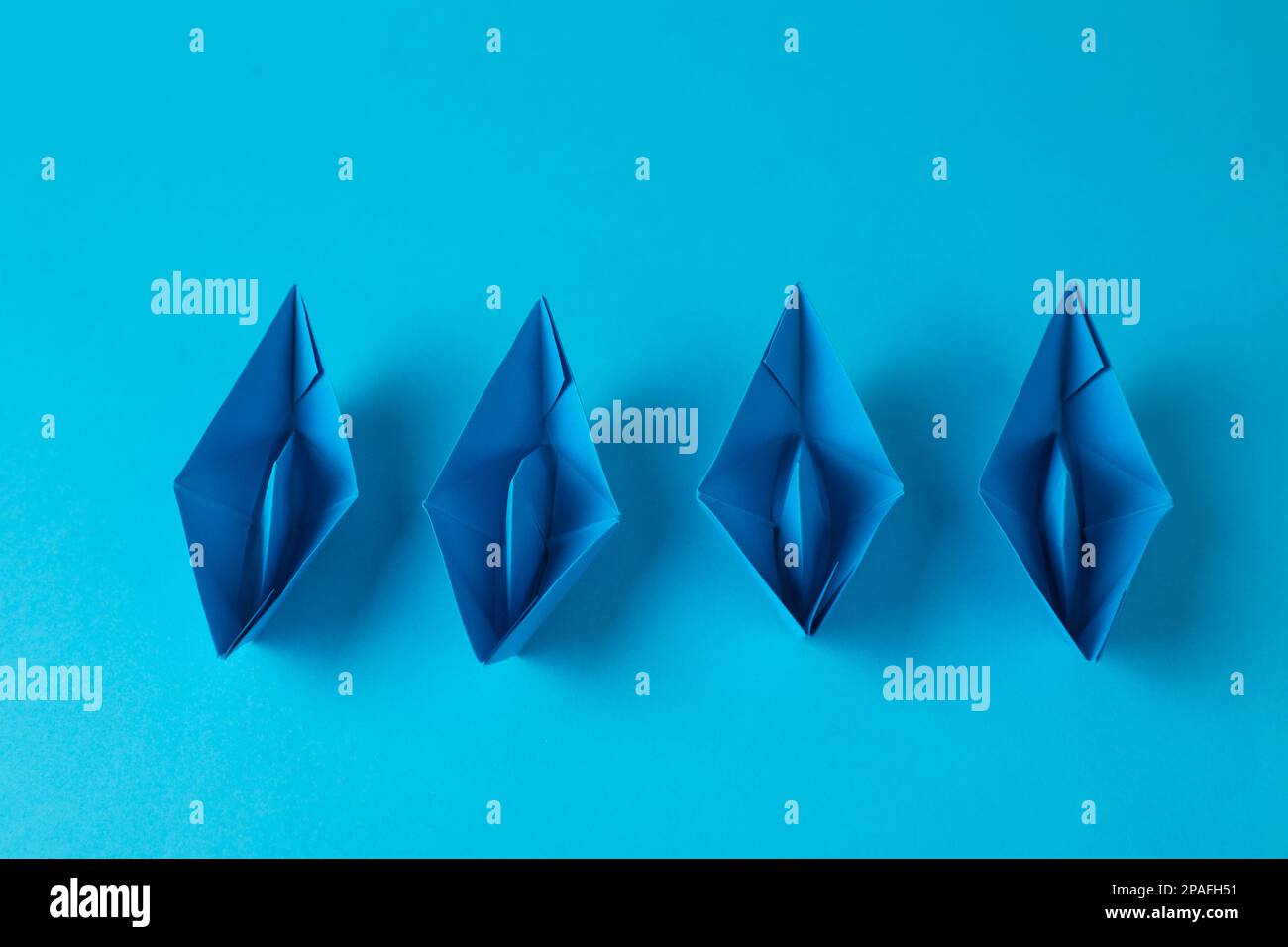 Handmade paper boats on light blue background, flat lay. Origami art ...