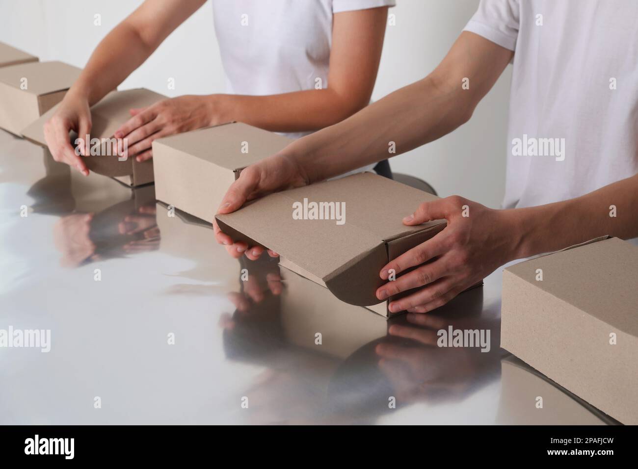 Workers folding cardboard boxes at table, closeup. Production line ...