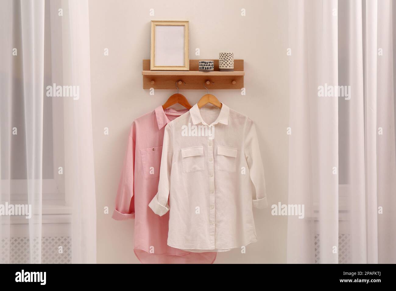 Wooden shelf with fashionable clothes and decorative elements on light ...