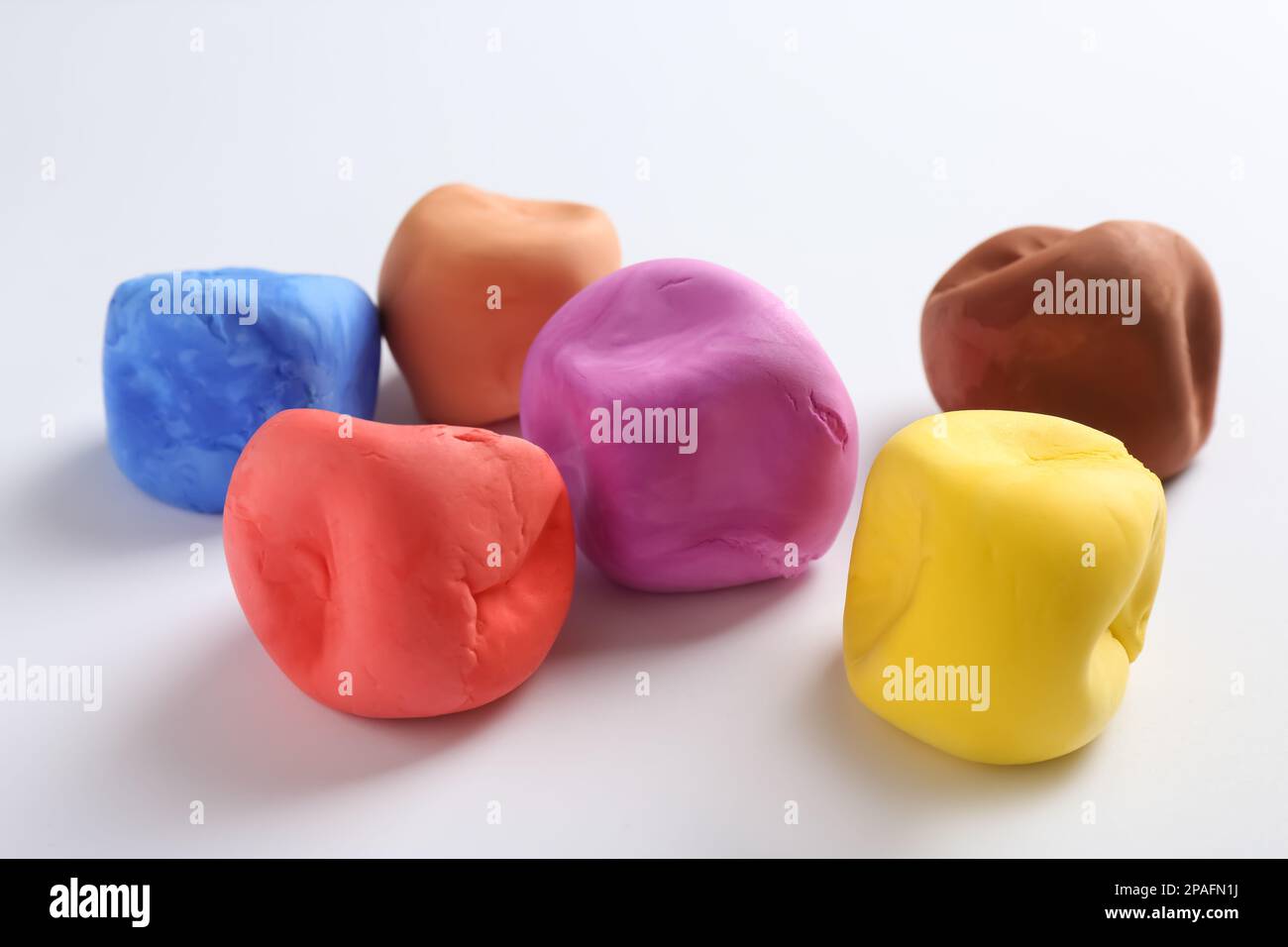 Different color play dough on white background Stock Photo - Alamy
