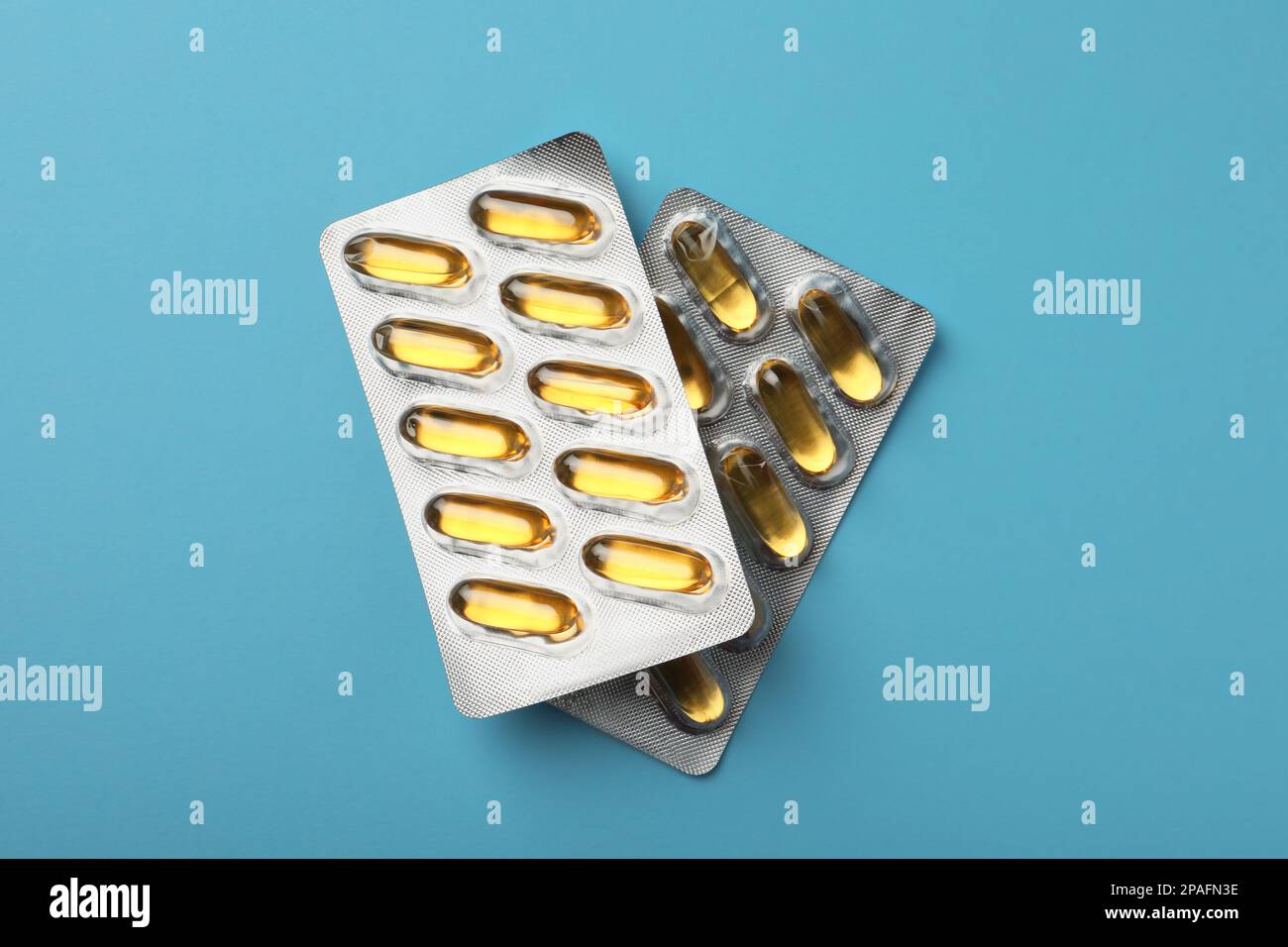 Dietary supplement capsules in blister packs on light blue background ...