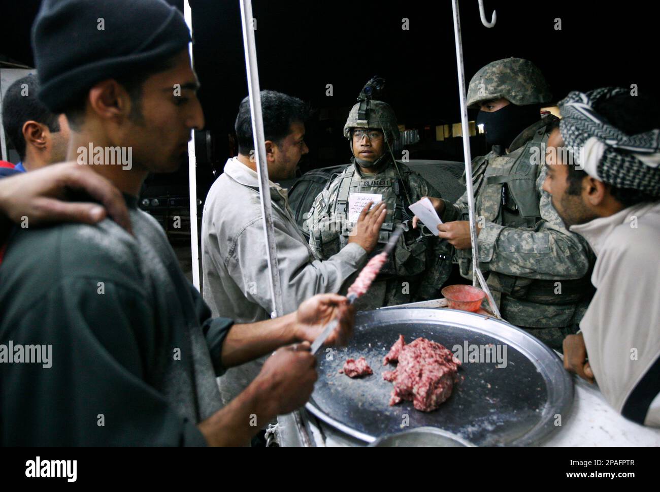 Iraqi men gather at a Kebab stall as U.S. Army soldiers with the 2nd ...