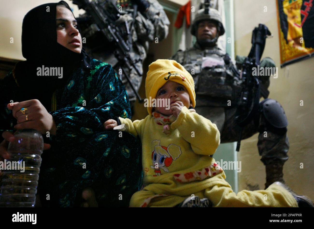 An Iraqi girl and her mother look on as U.S. Army soldiers with the 2nd ...