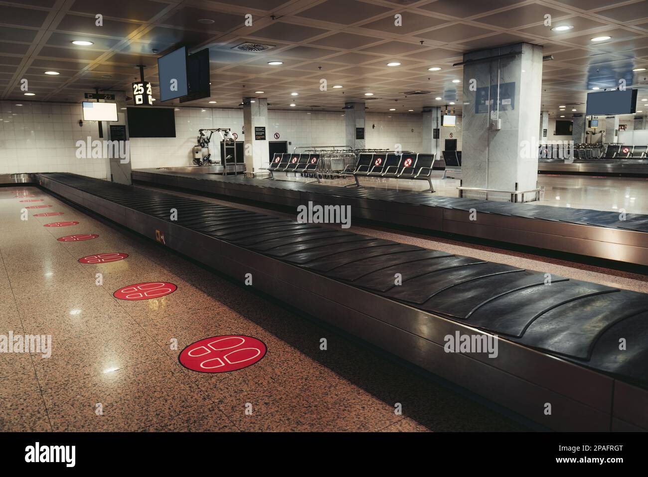 An empty baggage claim zone in an airport terminal with rows of seats ...
