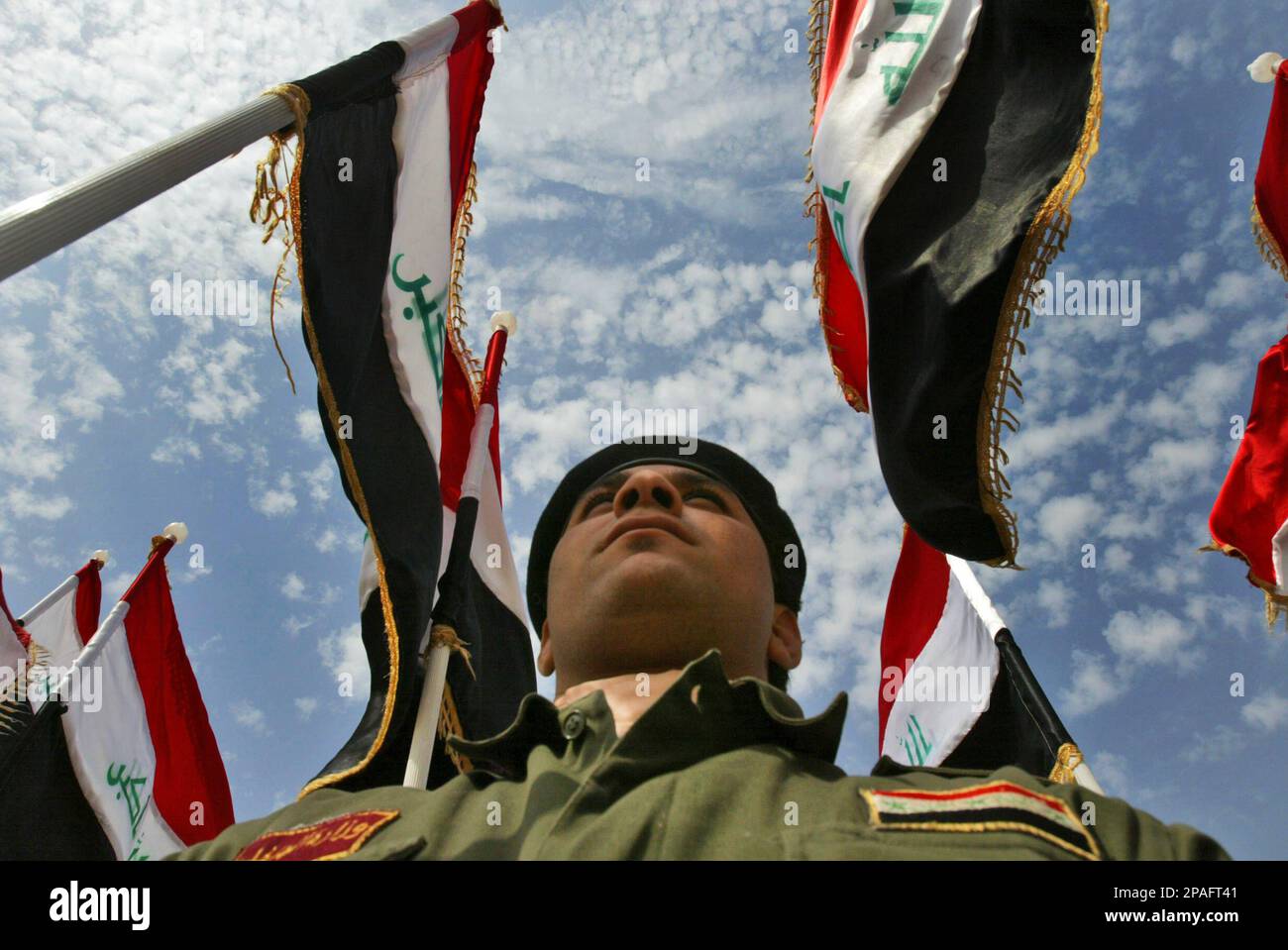 Iraqi police graduate stands at attention as national flags flutter ...