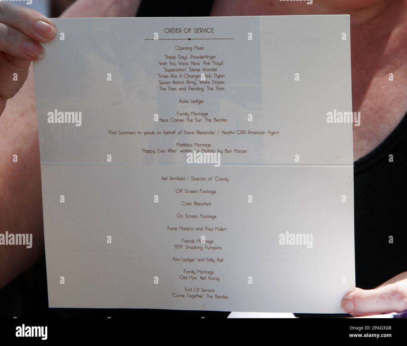 A woman displays the program of a memorial service for the late ...