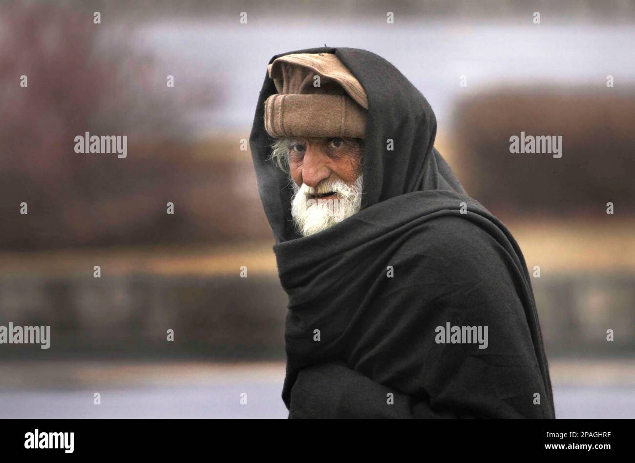 An elder Pakistani walks through a chilly morning fog in Islamabad ...