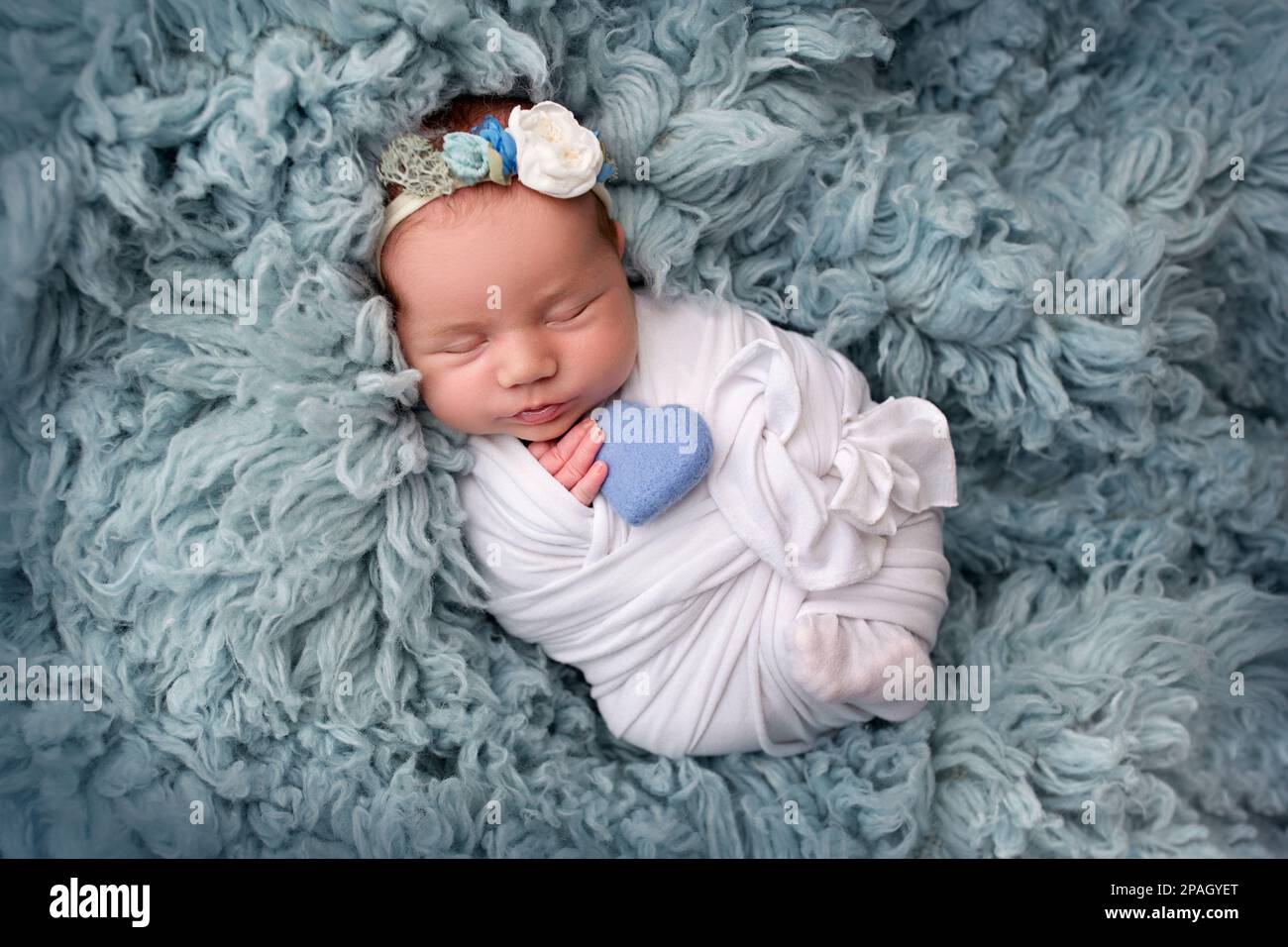 Top view of a newborn baby girl sleeping in a white winding with ...