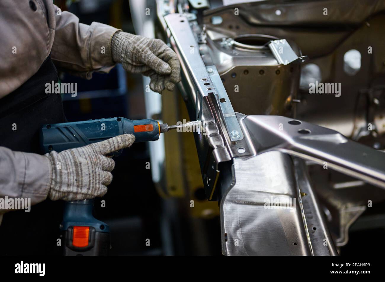 Worker prepares to screw car body parts on workshop conveyor Stock ...