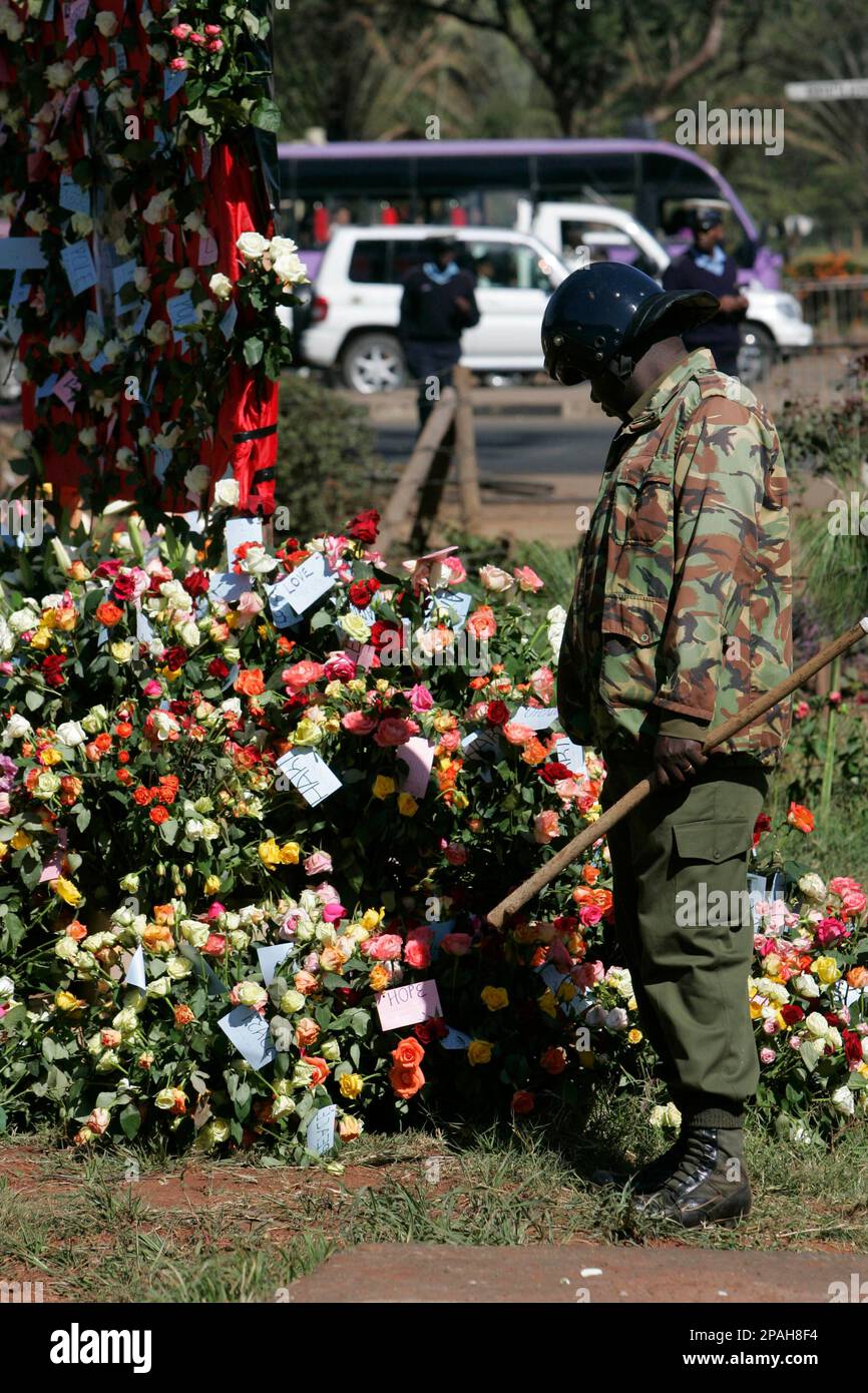 A riot police officer looks at flowers laid by human right activist ...