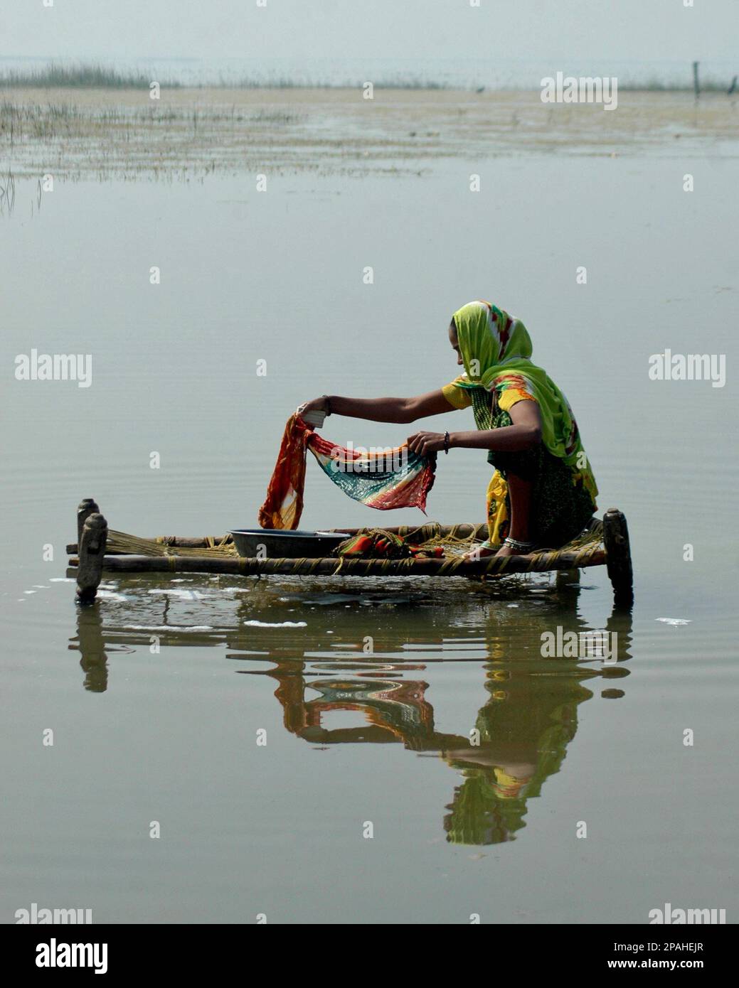 An Indian woman washes clothes at Nal Sarovar bird sanctuary, the ...