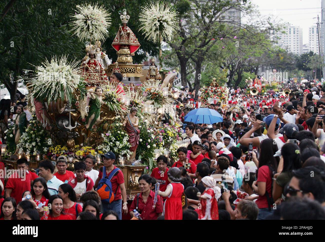 Thousands of devotees line up to watch the procession of the images of ...