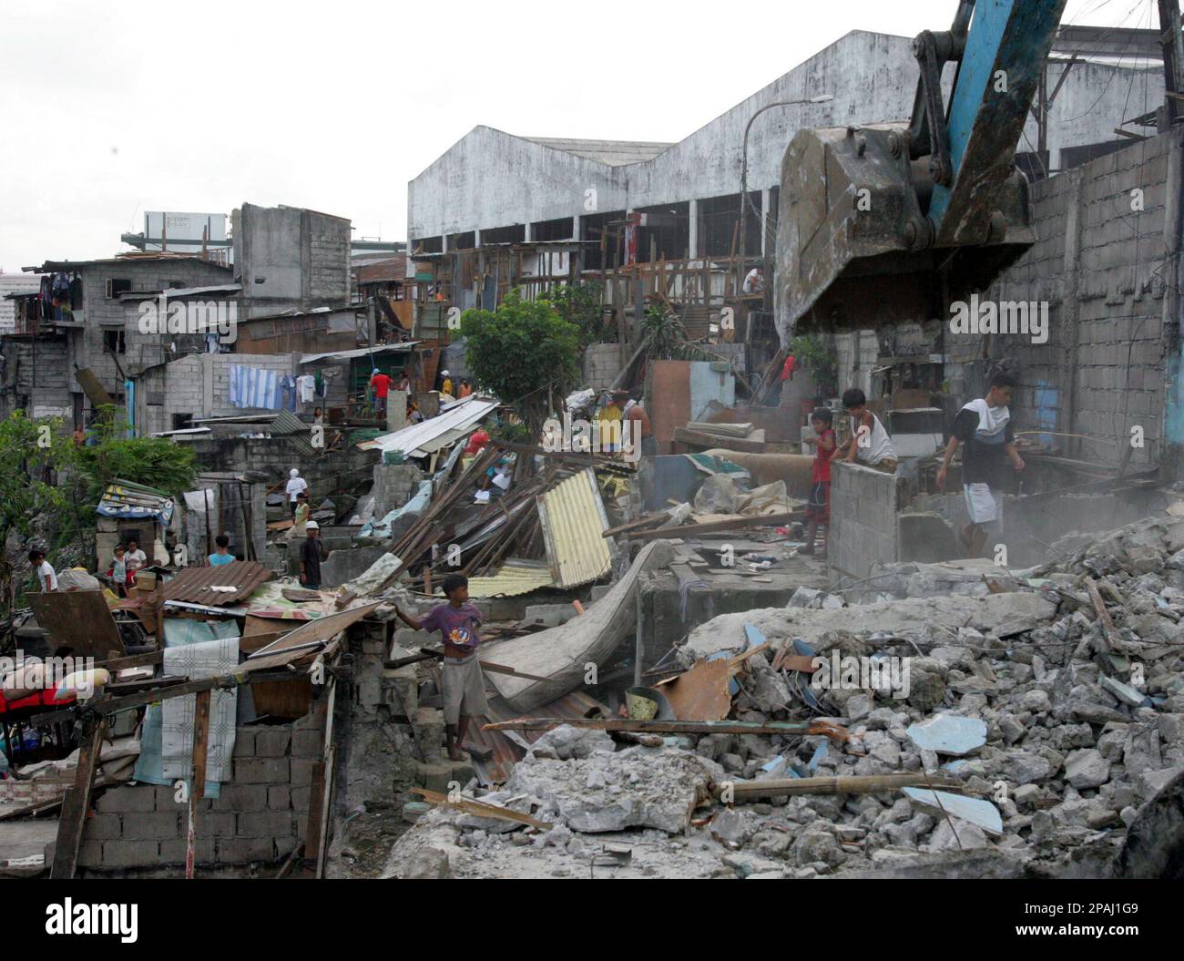 A buck hoe used to demolish squatter homes is seen at right, as local ...