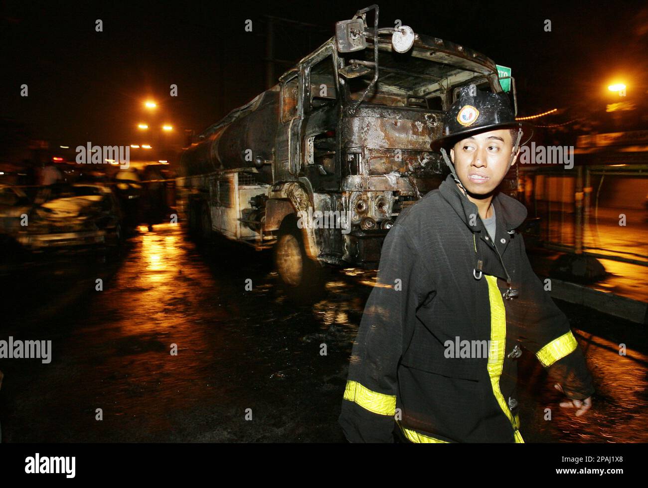 A Filipino firefighter walks in front of the remains of a fuel truck ...