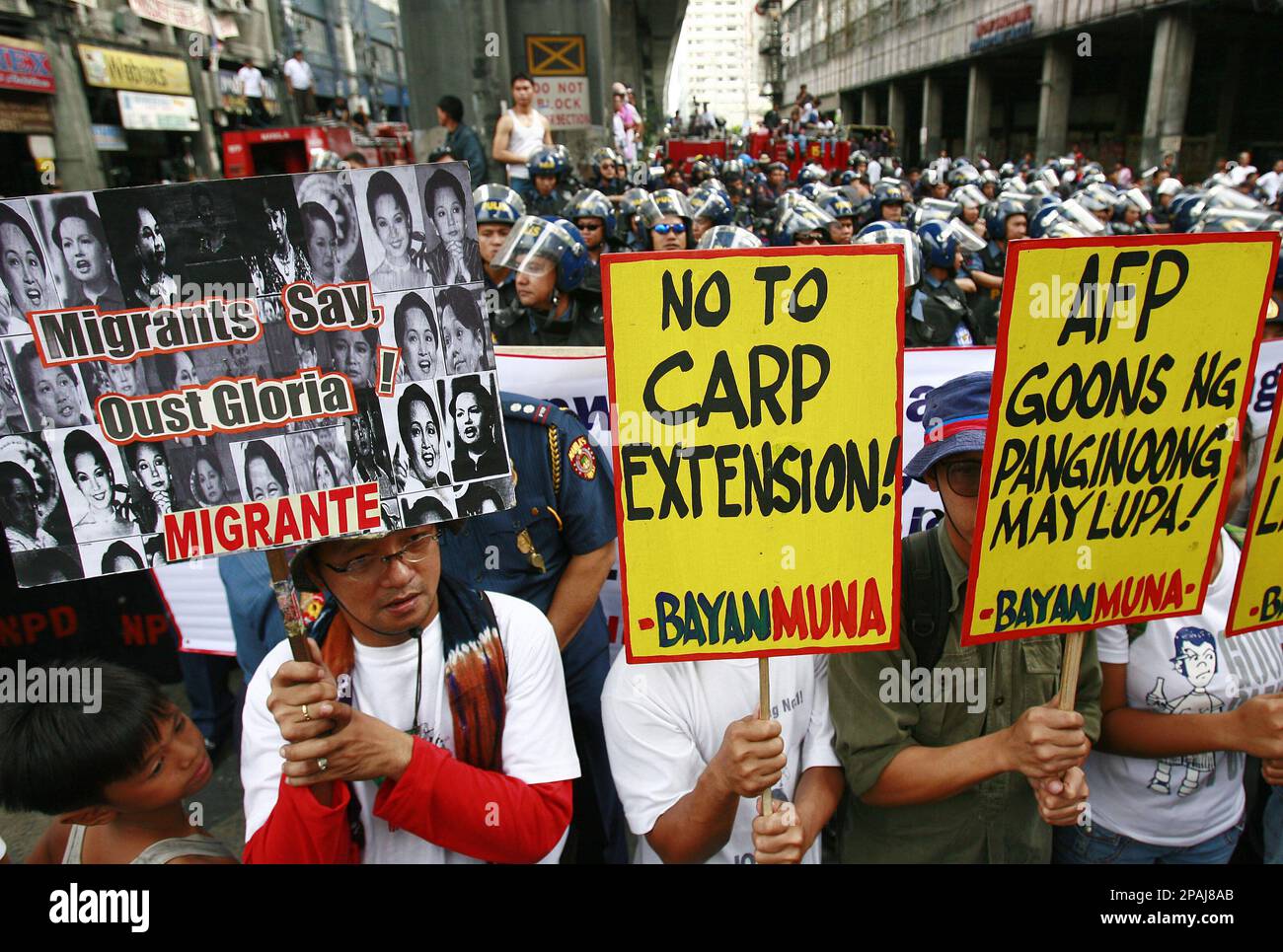 Protesters holds signs in front of Philippine riot police during a ...