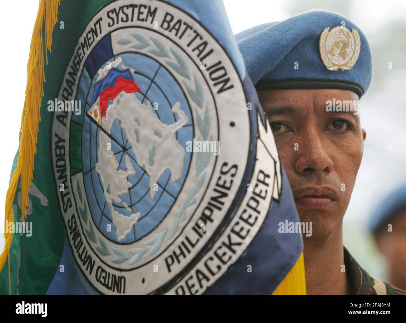 A soldier stands at attention beside their contingent flag during the ...