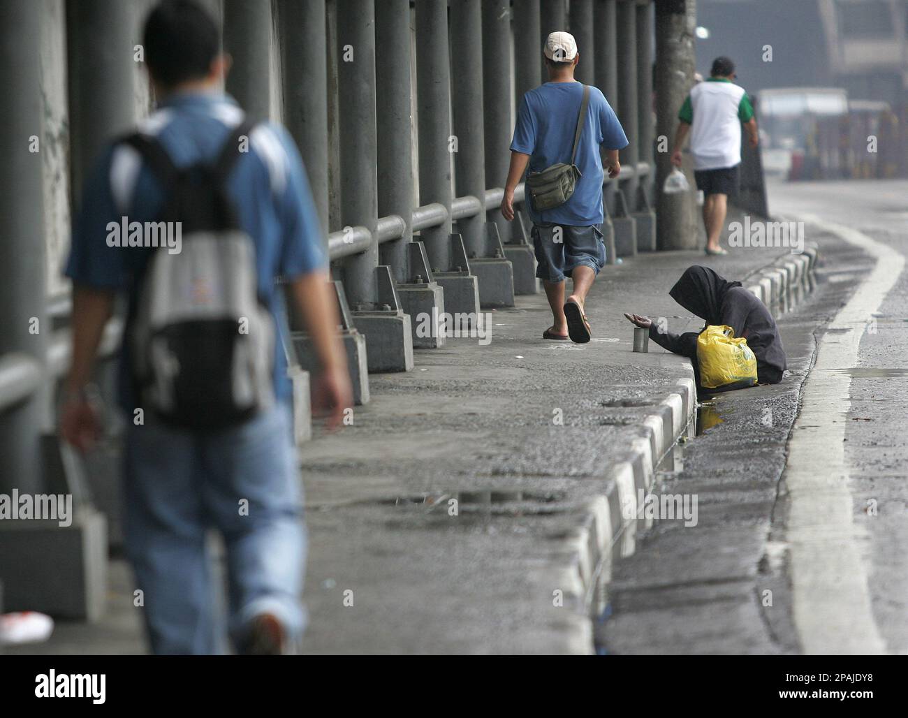 A poor Filipino woman begs along a street in suburban Manila ...