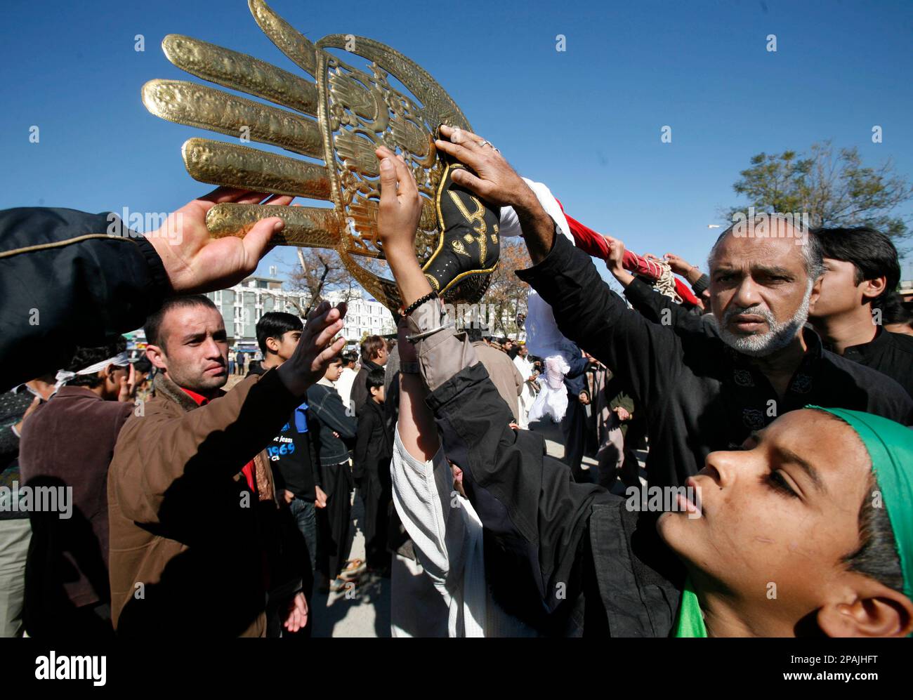 Pakistani Shia Muslims reach up to touch a religious symbol as part of ...