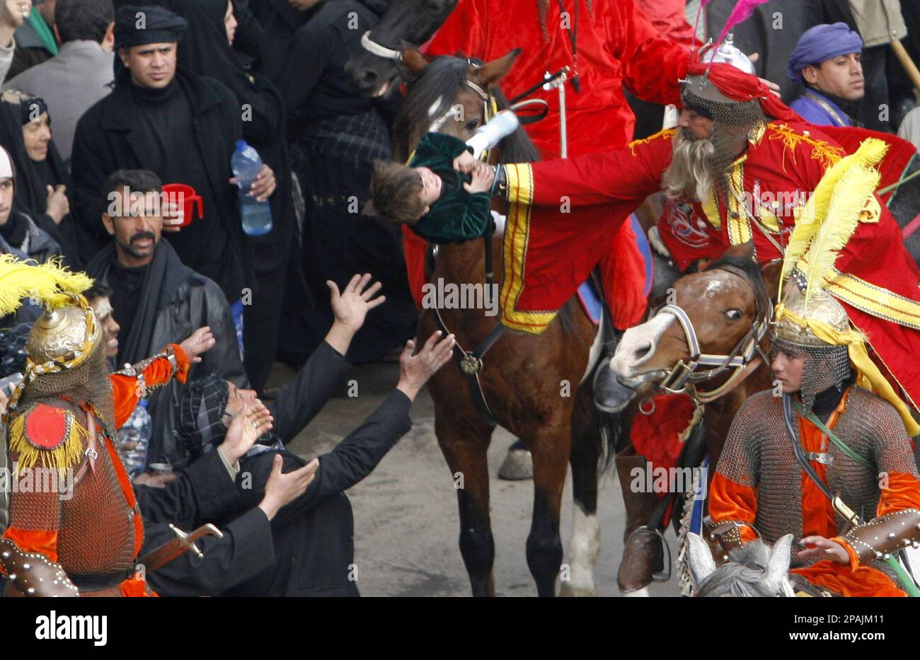 A performer re-enacting the Battle of Karbala tosses a child as part of ...