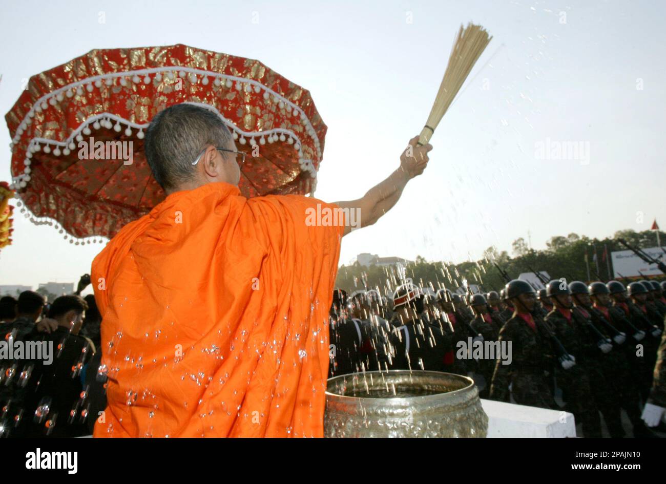 A Buddhist monk splashes holy water on Thai soldiers marching past ...