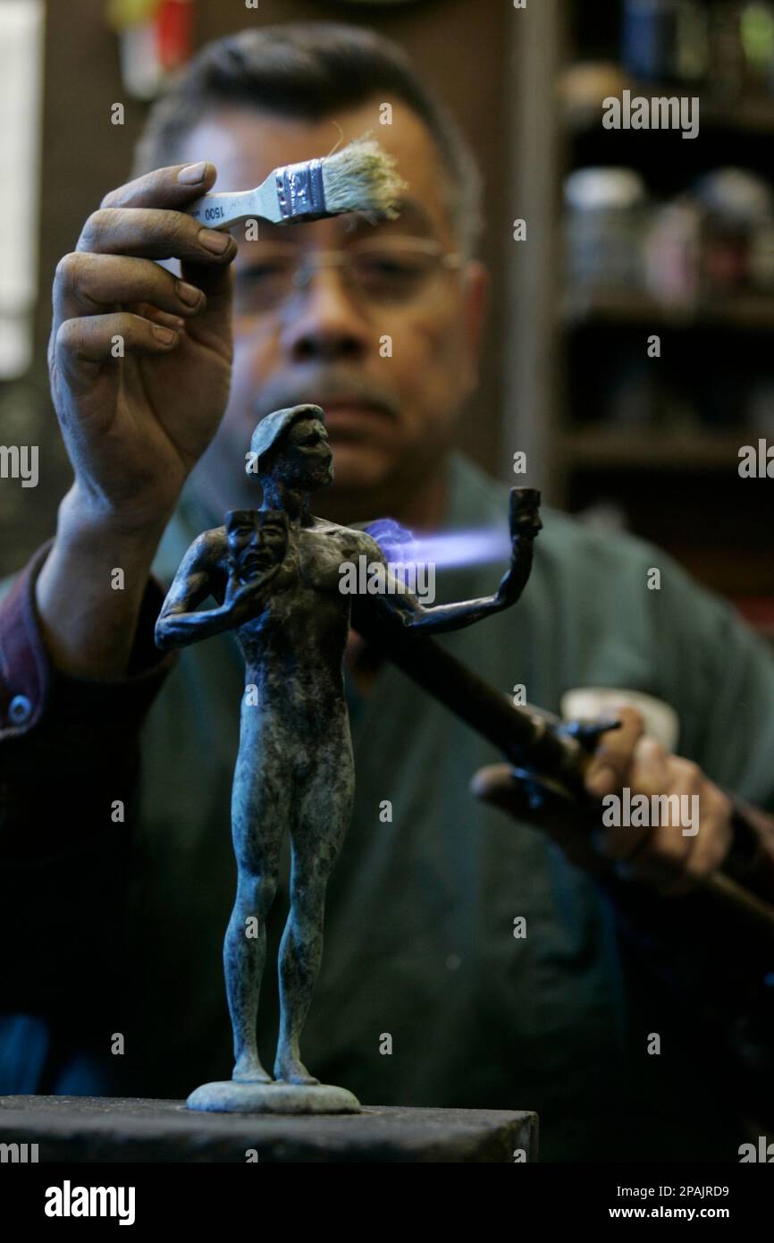 Artist Joaquin Quintero applies a green-black patina finish to a ...