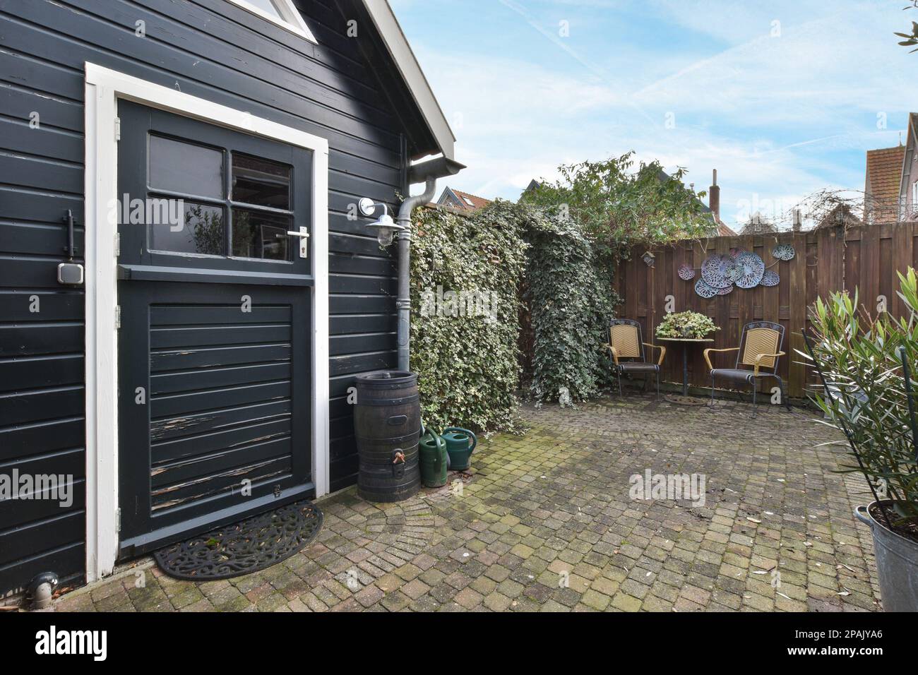 a back yard with an open door and potted plants on the brick path ...