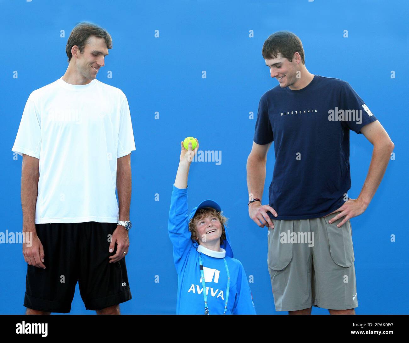 Ballboy Justin Hynes looks up at tennis players Ivo Karlovic, left, and ...