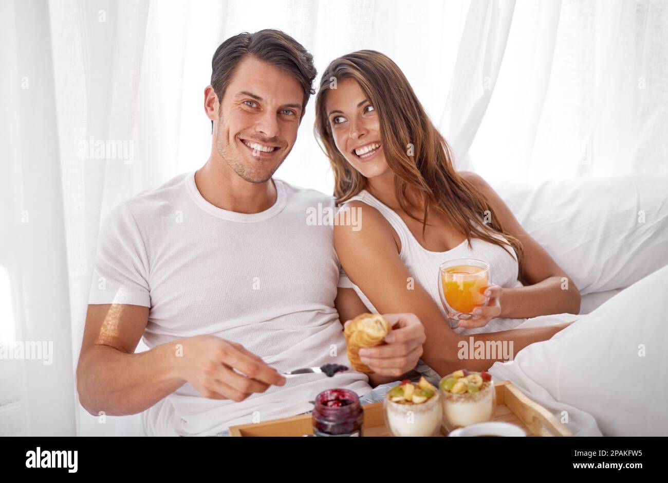 Breakfast in bed, portrait and morning couple relax with food, love bond and enjoy quality time ...