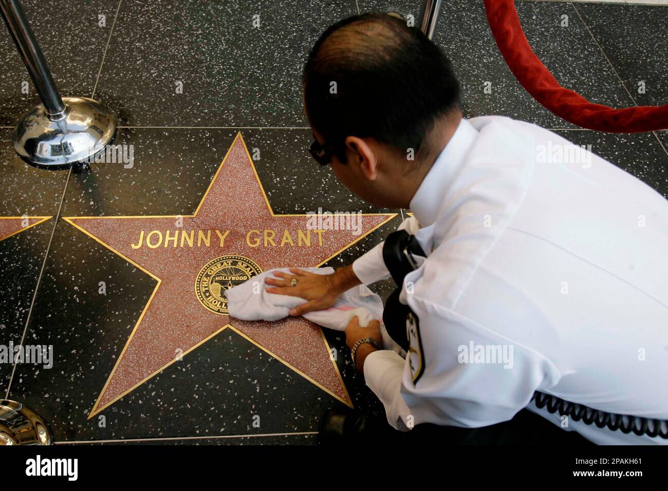 A unidentified security guard polishes the star of Johnny Grant on the ...
