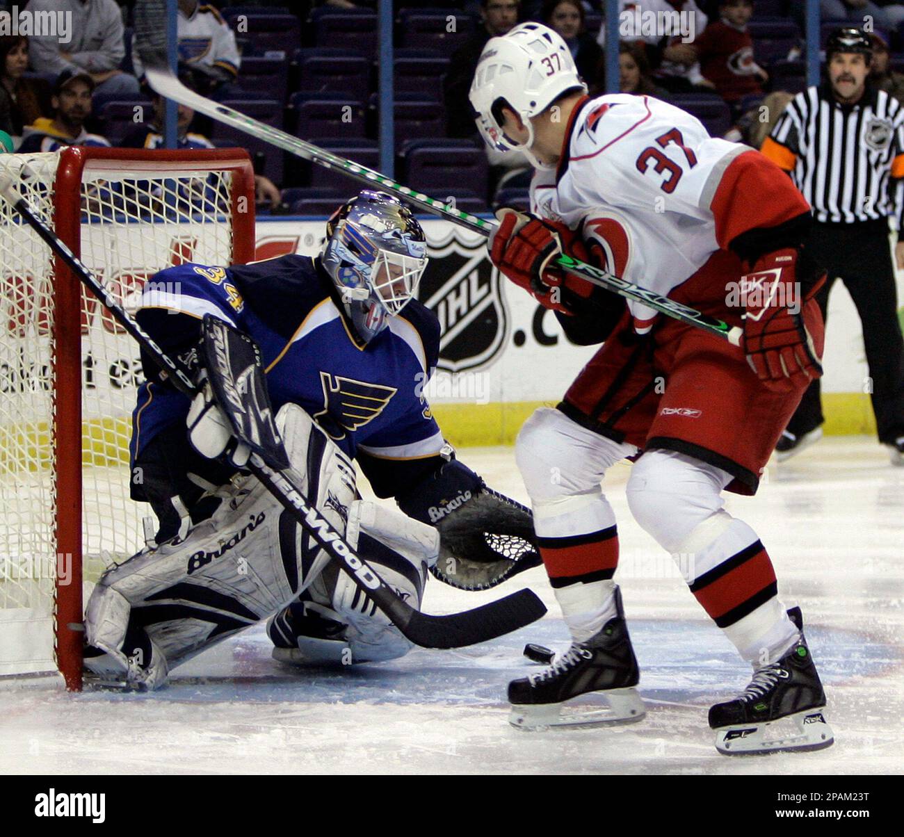 St. Louis Blues goalie Manny Legace, left, tries to grab a loose puck ...