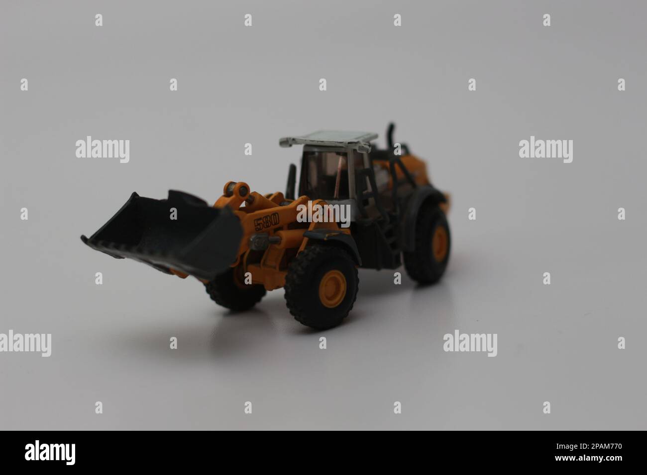 a close up of miniature orange wheel loader toy isolated on white ...
