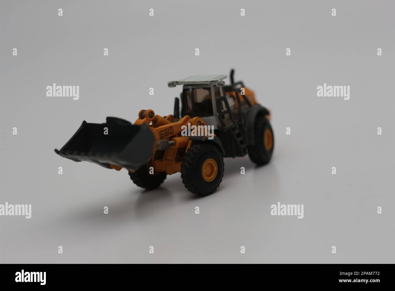 a close up of miniature orange wheel loader toy isolated on white ...
