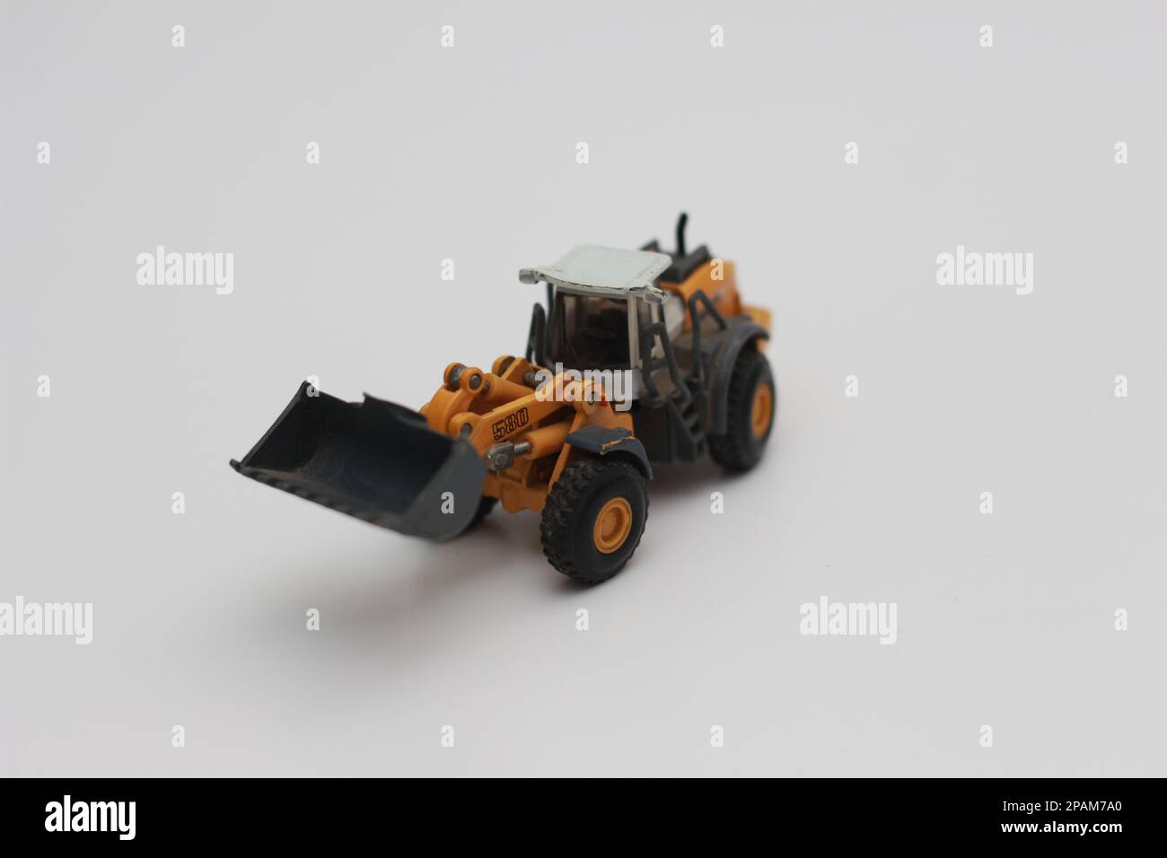 a close up of miniature orange wheel loader toy isolated on white ...