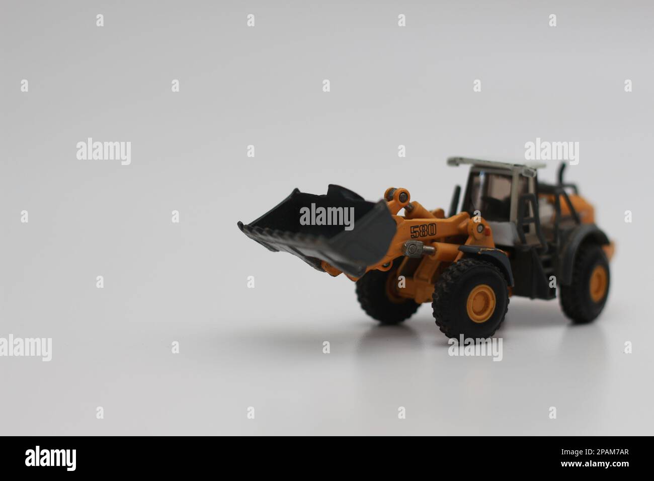 a close up of miniature orange wheel loader toy isolated on white ...