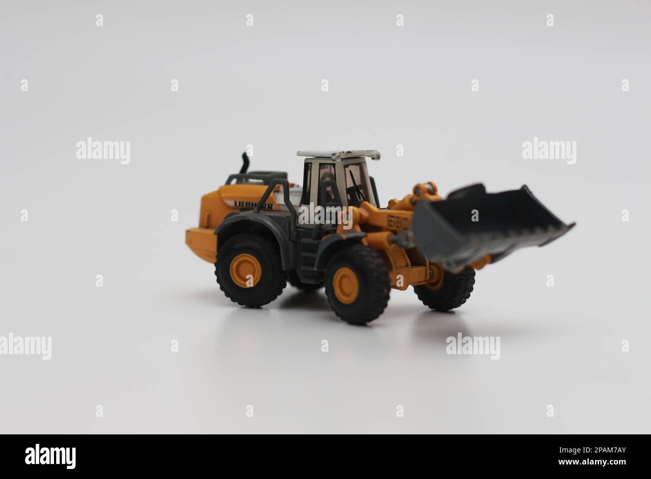 a close up of miniature orange wheel loader toy isolated on white ...