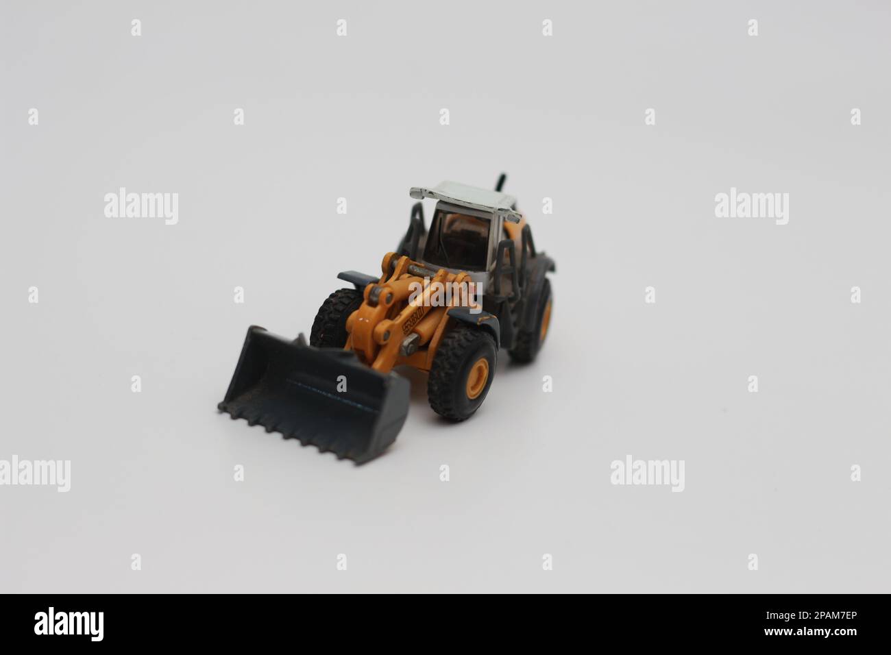 a close up of miniature orange wheel loader toy isolated on white ...
